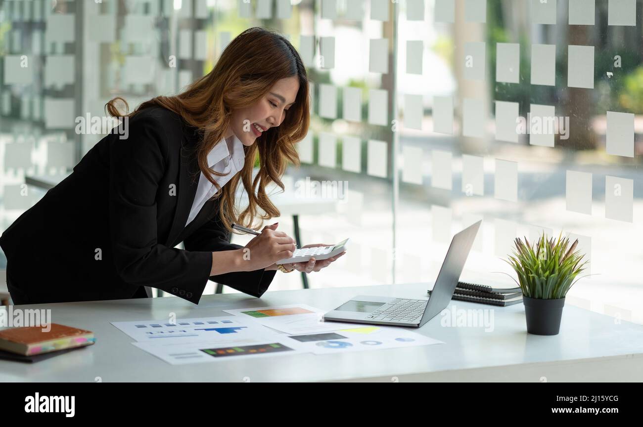 Business asian woman working on calculator and laptop computer ...