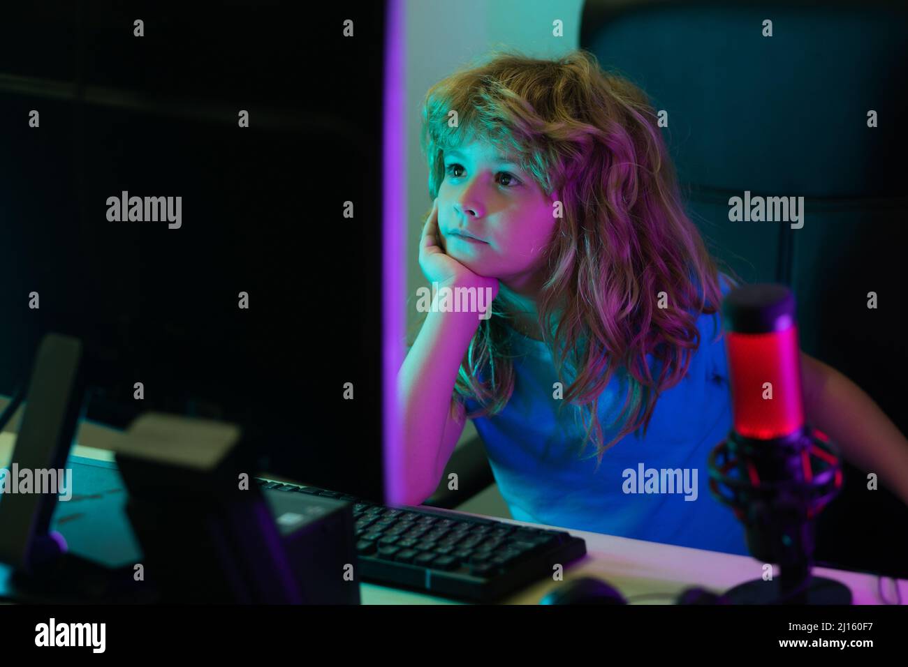 Kid using pc at night. Child with computer in a dark room. Portrait of ...