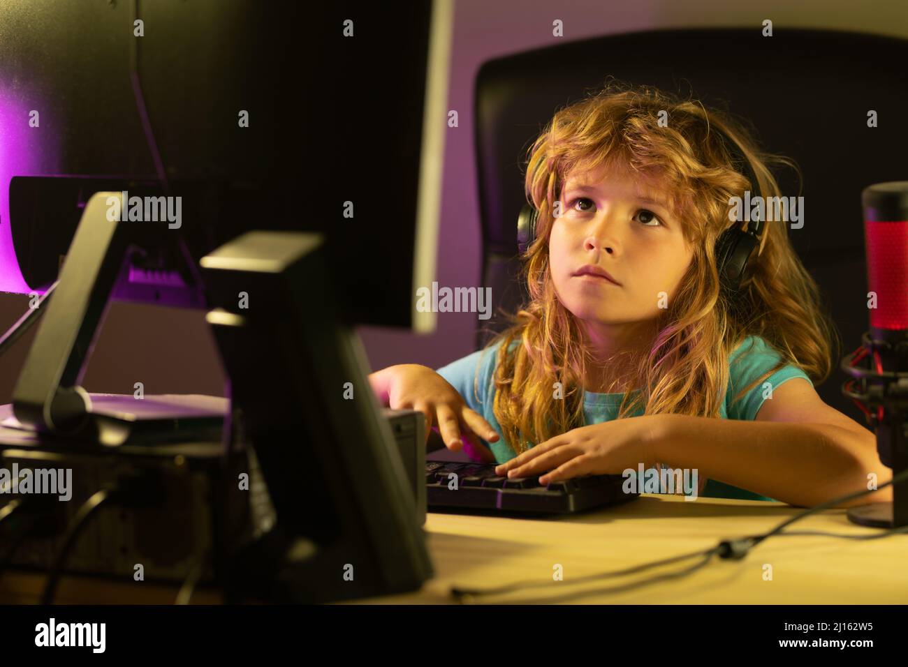 A little boy child uses a desktop at night, a child with computer ...