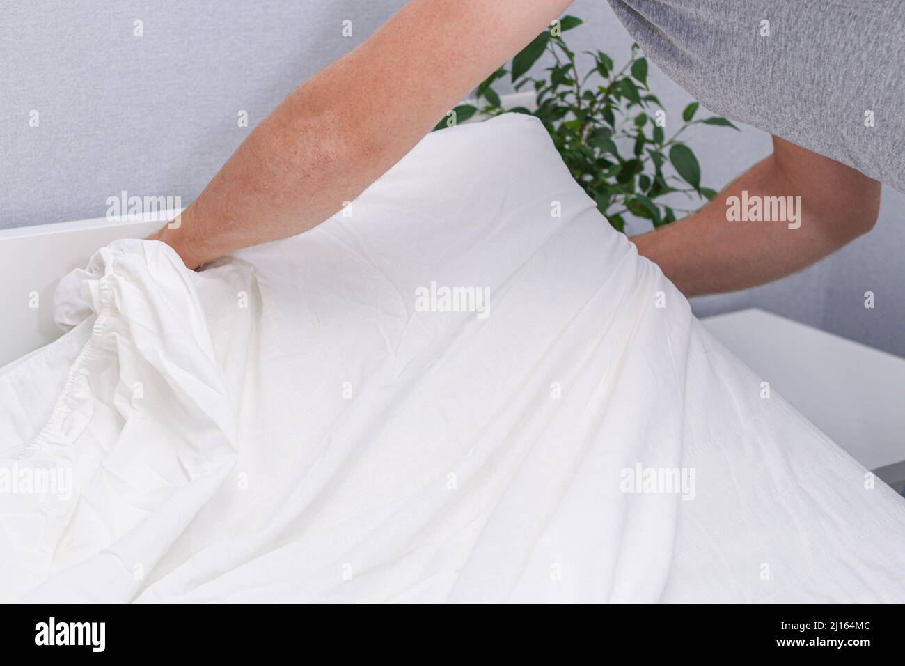 A man puts an elasticated sheet on the mattress. Change of bed linen ...