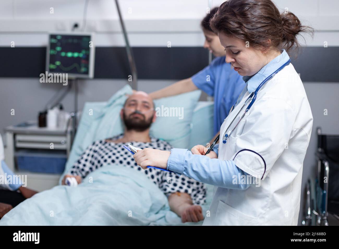 Doctor with stethoscope reading medical chart while nurse is making ...