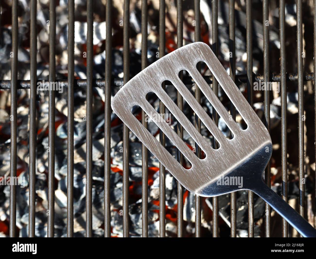 stainless steel spatula on empty barbecue grill grate over glowing ...