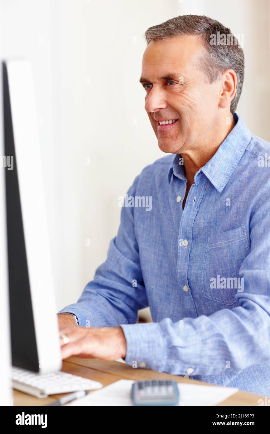 Smiling Mature Man Calculating Expenses Using Computer Portrait Of A Smiling Mature Man