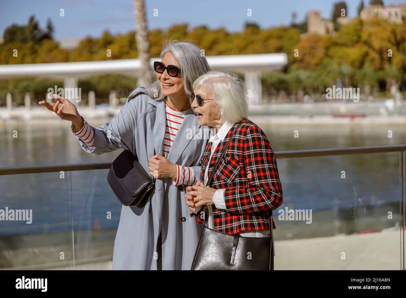 Female friends having conversation on promenade by sea Stock Photo - Alamy