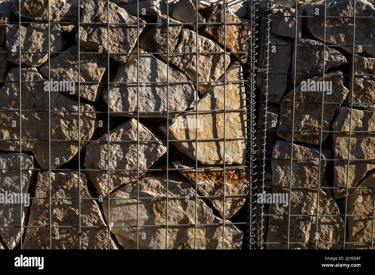 Wall of stones held by a metal mesh. Wide panoramic texture for ...