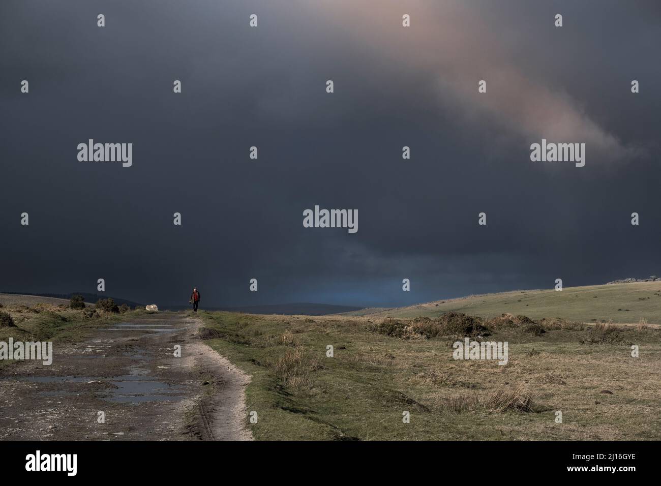 Dramatic storm clouds over a man walking along the remains of a disused ...