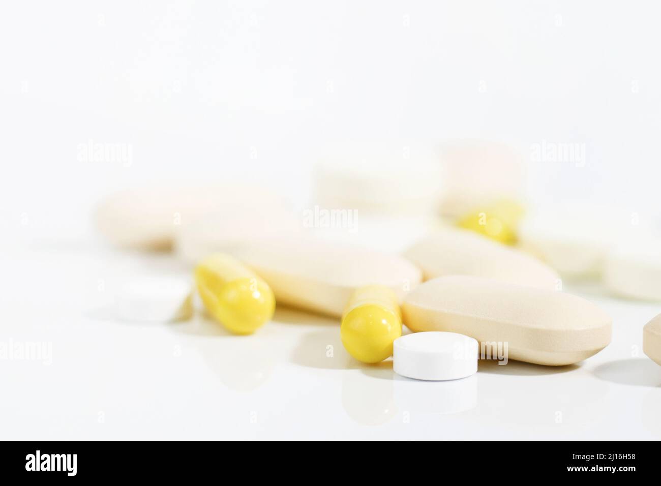 Tablets and capsules of different shapes and sizes on a white ...