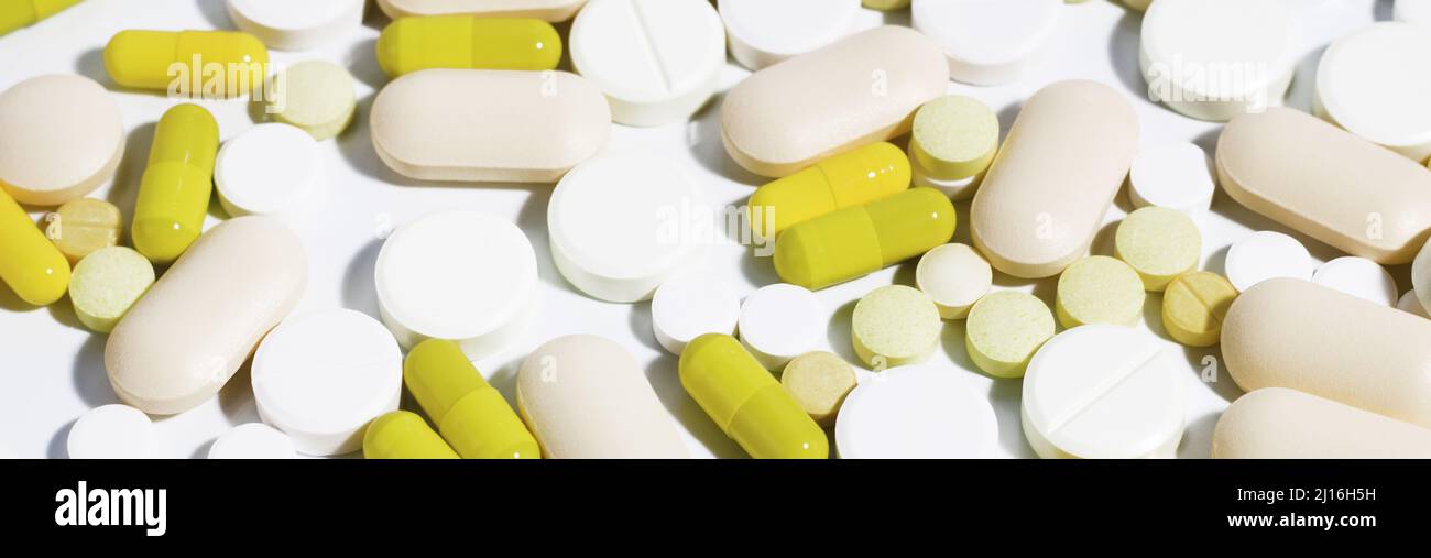Pills and capsules of different shapes and sizes are isolated on a ...