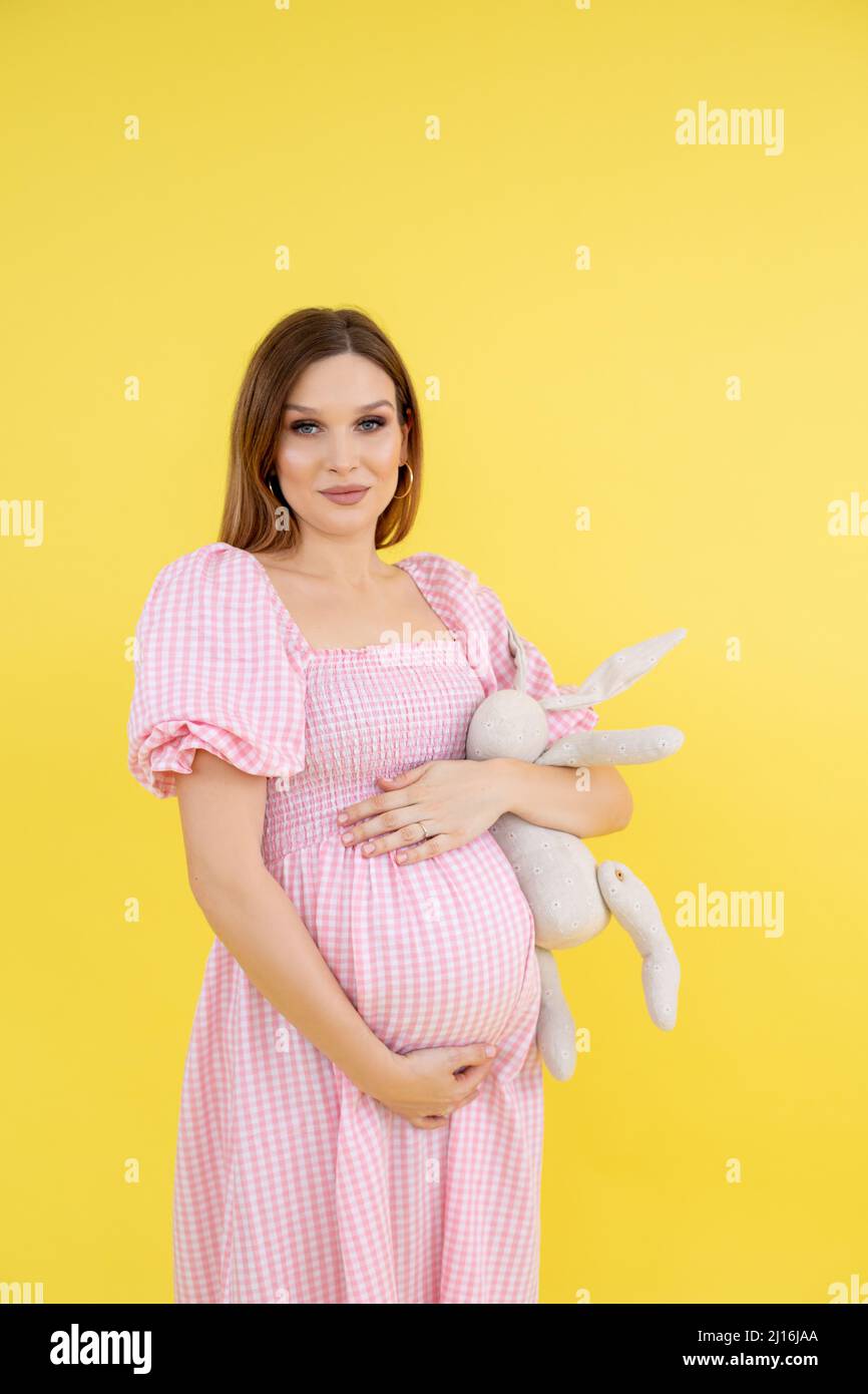 Young attractive pregnant woman wearing pink and white gingham dress ...