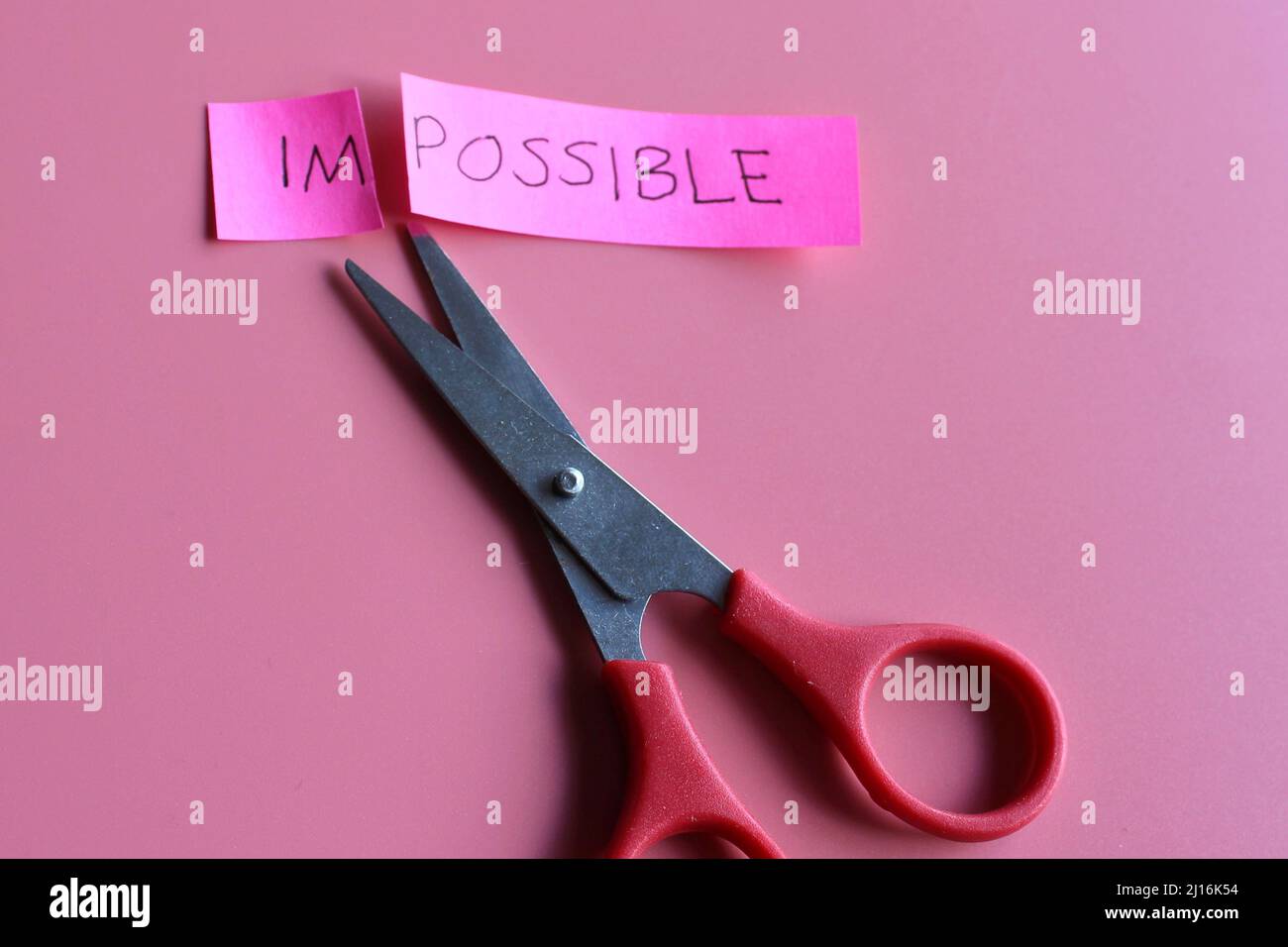 Cutting the word impossible to possible on pink background, concept for ...