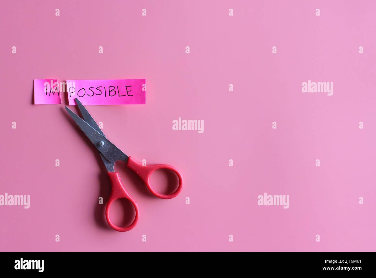 Cutting the word impossible to possible on pink background, concept for ...