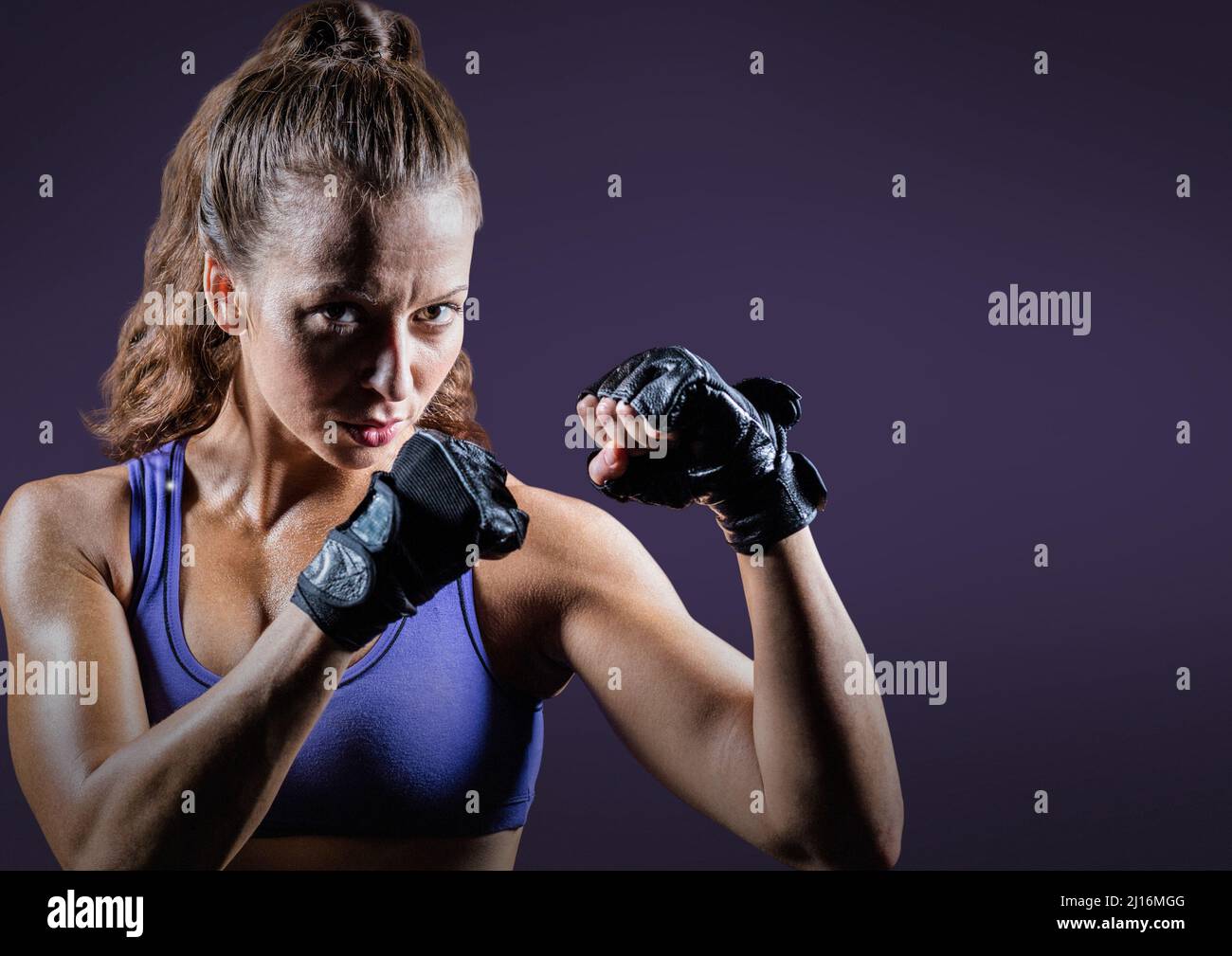 Portrait of caucasian female boxer against copy space on purple ...