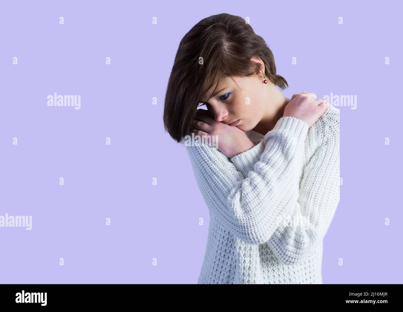 Caucasian shy woman hugging herself against copy space on purple ...