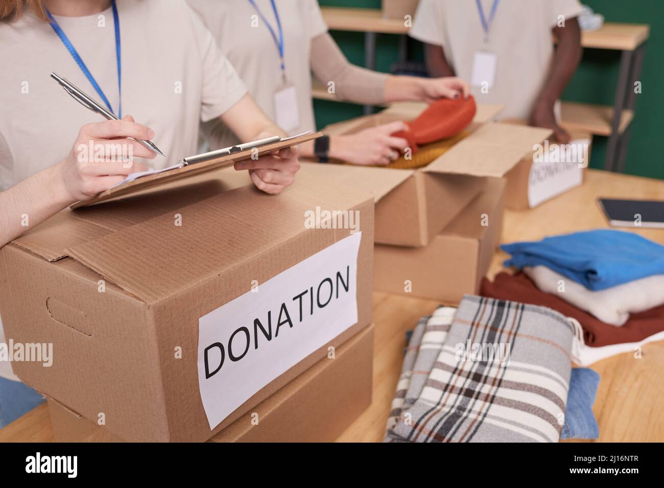 Group of unrecognizable young people volunteering in clothes charity ...