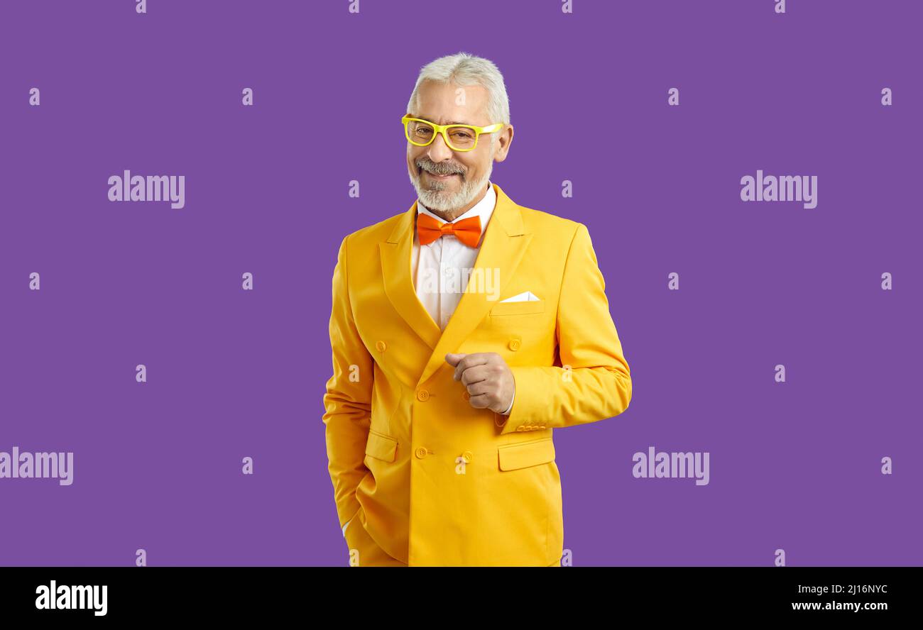 Happy senior man in yellow suit, bow tie and glasses standing isolated ...