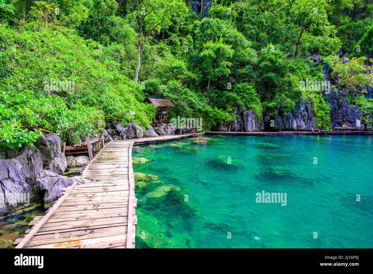Kayangan Lake - Blue crystal water in paradise lagoon - walkway on wooden pier in tropical ...