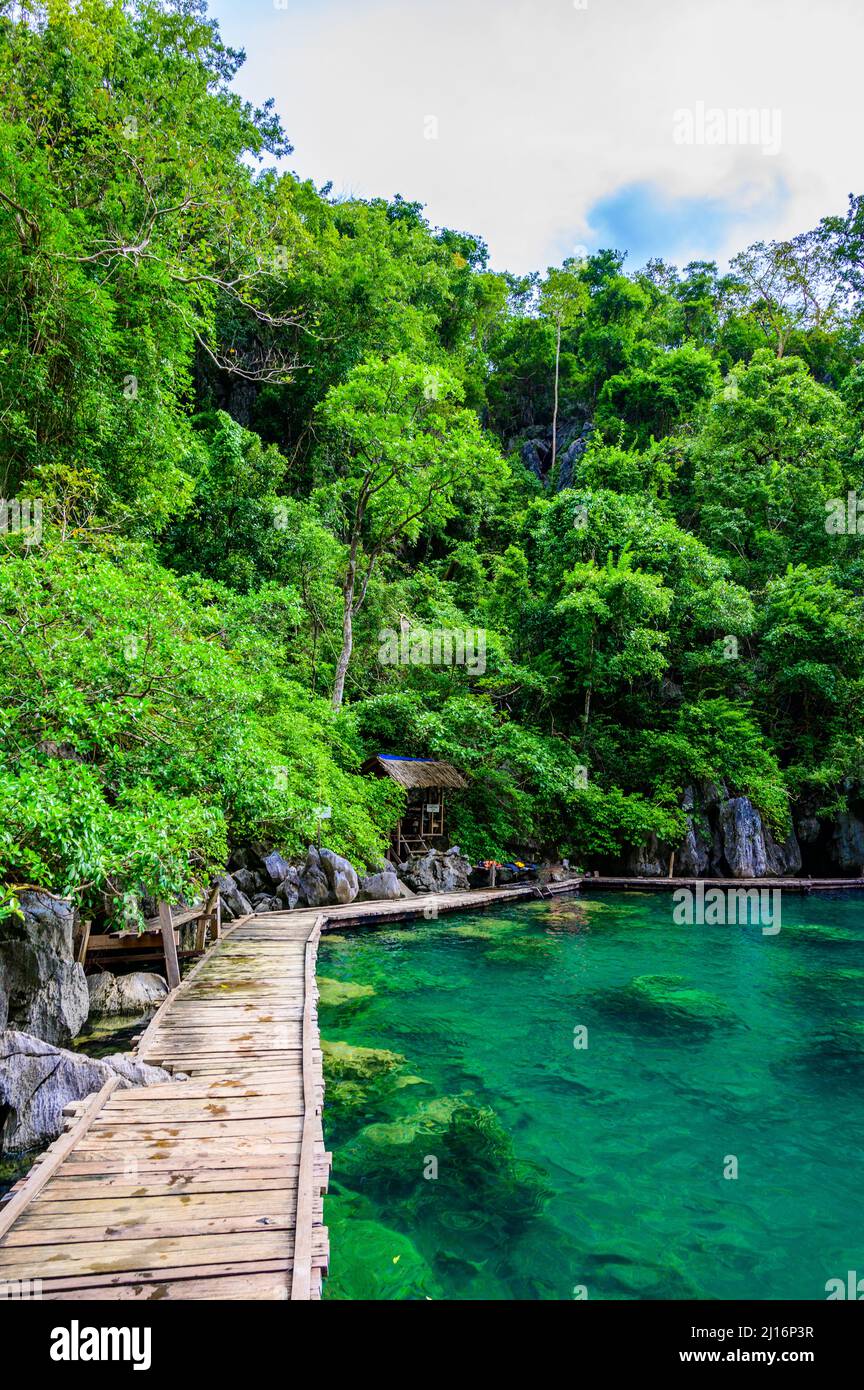Kayangan Lake - Blue crystal water in paradise lagoon - walkway on wooden pier in tropical ...