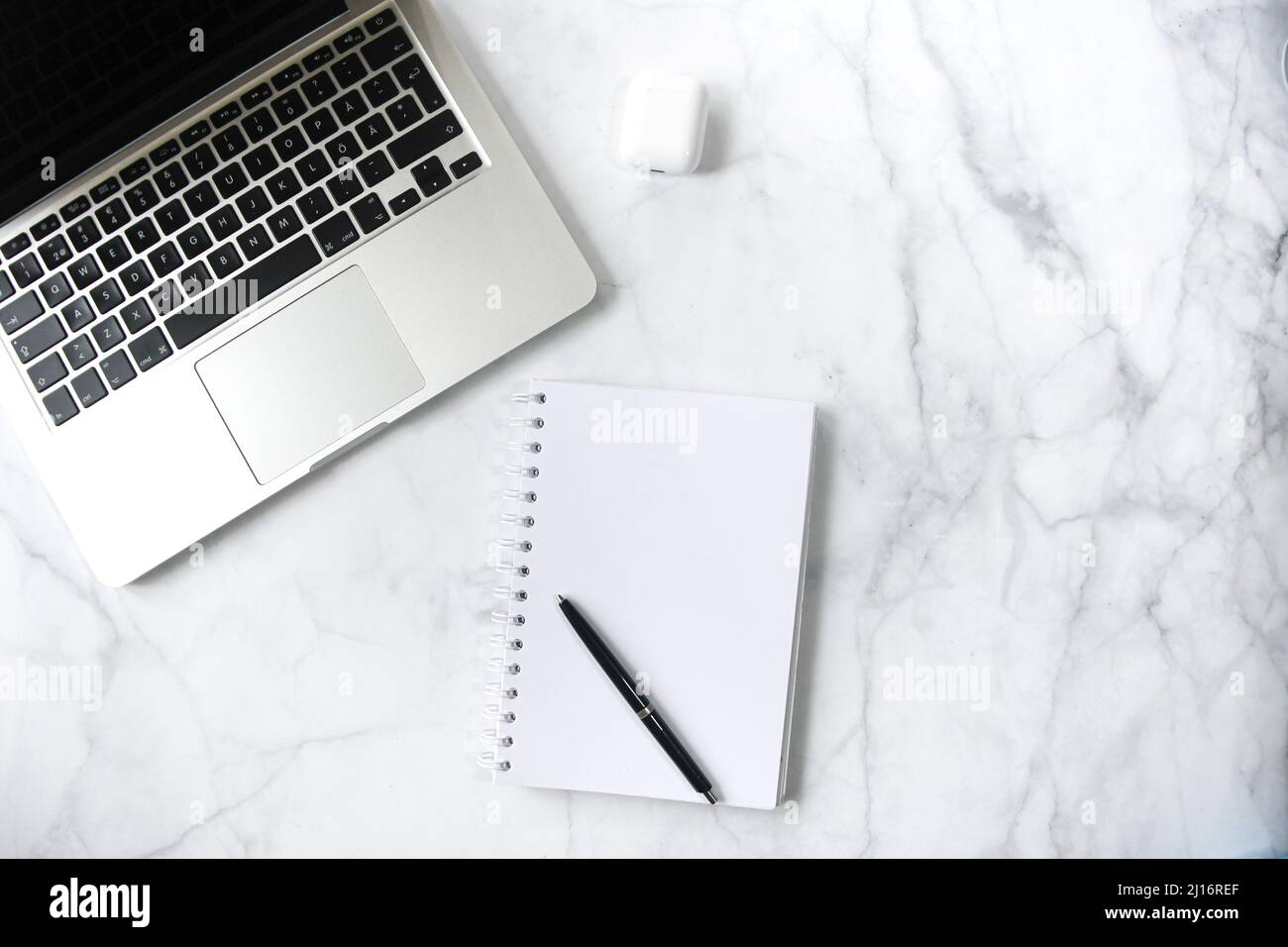 Overhead of laptop computer and notebook on white marble background ...