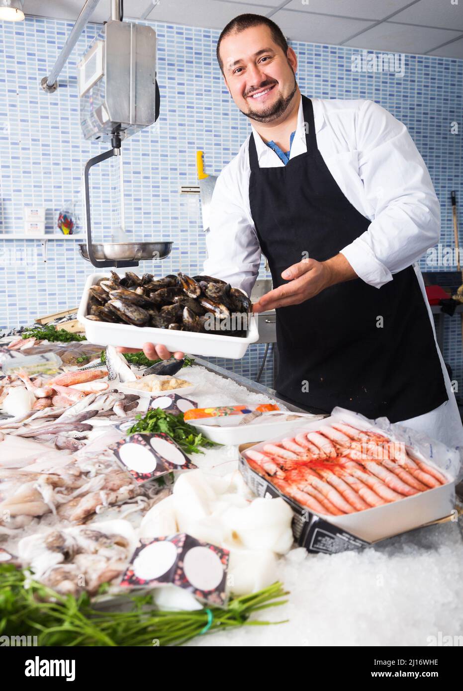 Smiling seller holds container of large mussels and smiling Stock Photo ...