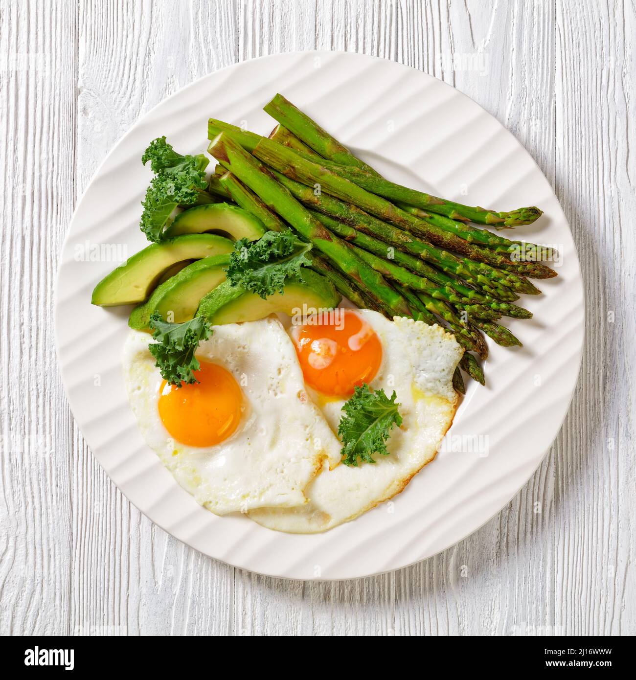 roast asparagus, fresh ripe avocado and fried eggs with runny yolks on ...