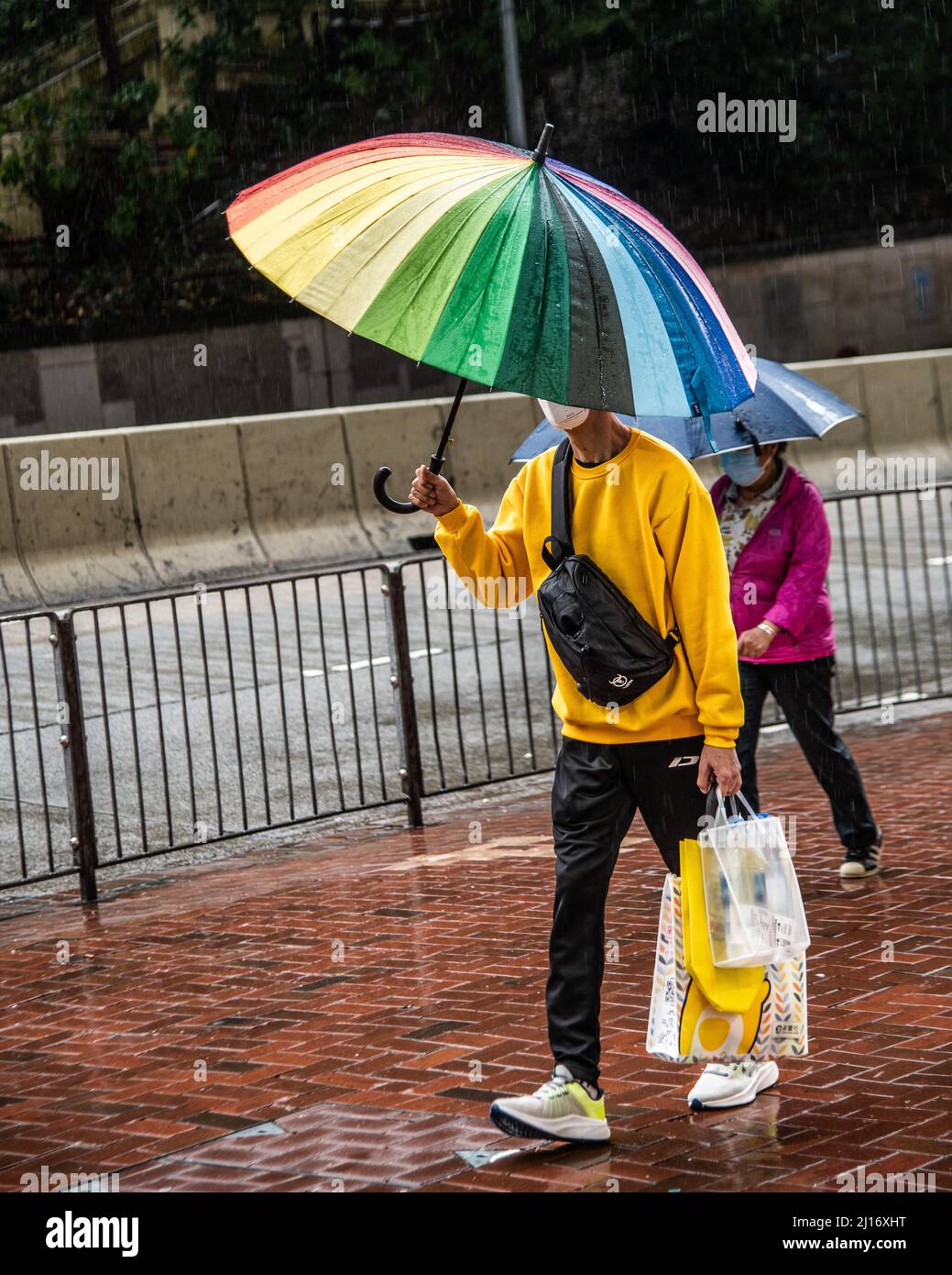 A shopper carrying a rainbow umbrella walks the streets as a northern ...