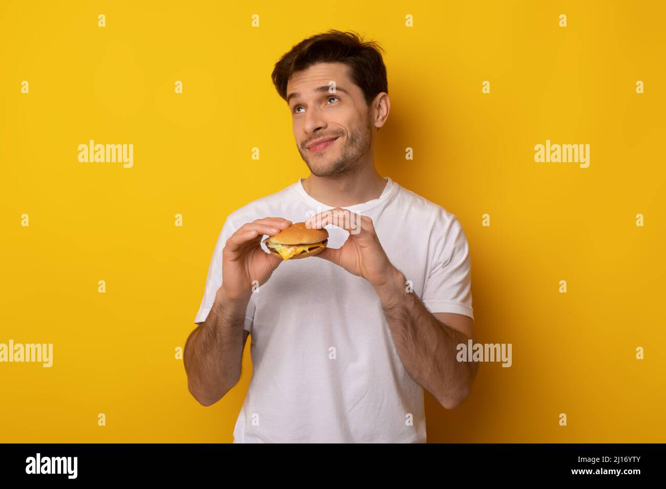 Funny Young Guy Holding Burger At Studio Stock Photo - Alamy