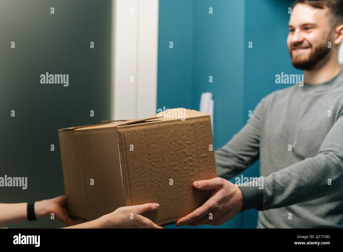 Friendly bearded courier male delivering cardboard box parcel to ...