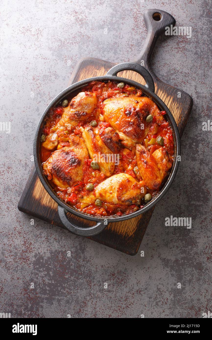 Baked chicken with sofrito vegetable sauce close-up in a frying pan on ...