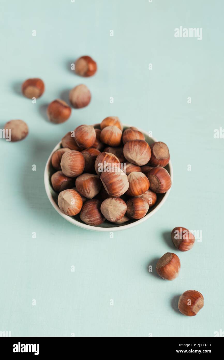 Pile of hazelnuts filbert in a bowl on a light blue background. Fresh ...