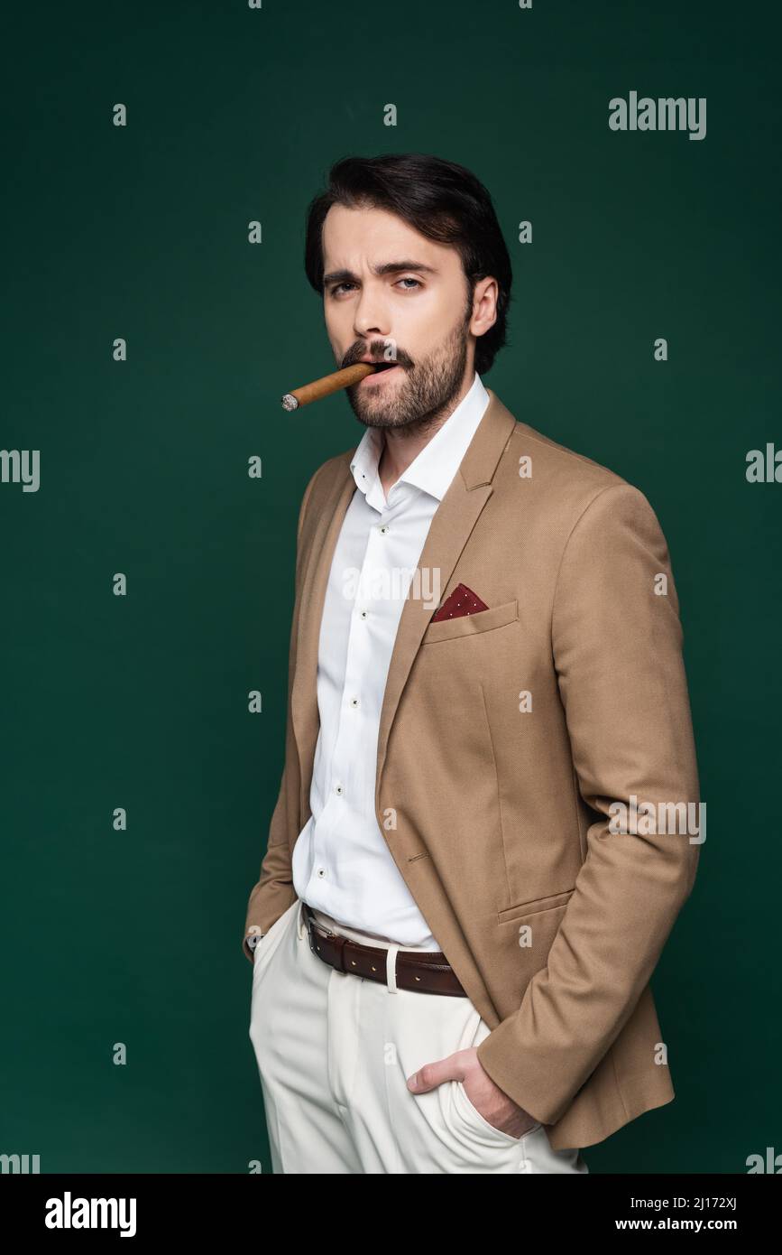 man with mustache smoking cigar and standing with hands in pockets on ...