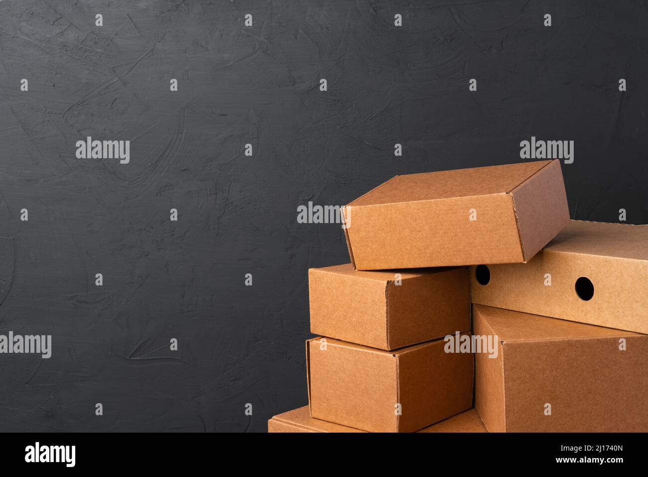 Stack of cardboard boxes against black background Stock Photo - Alamy