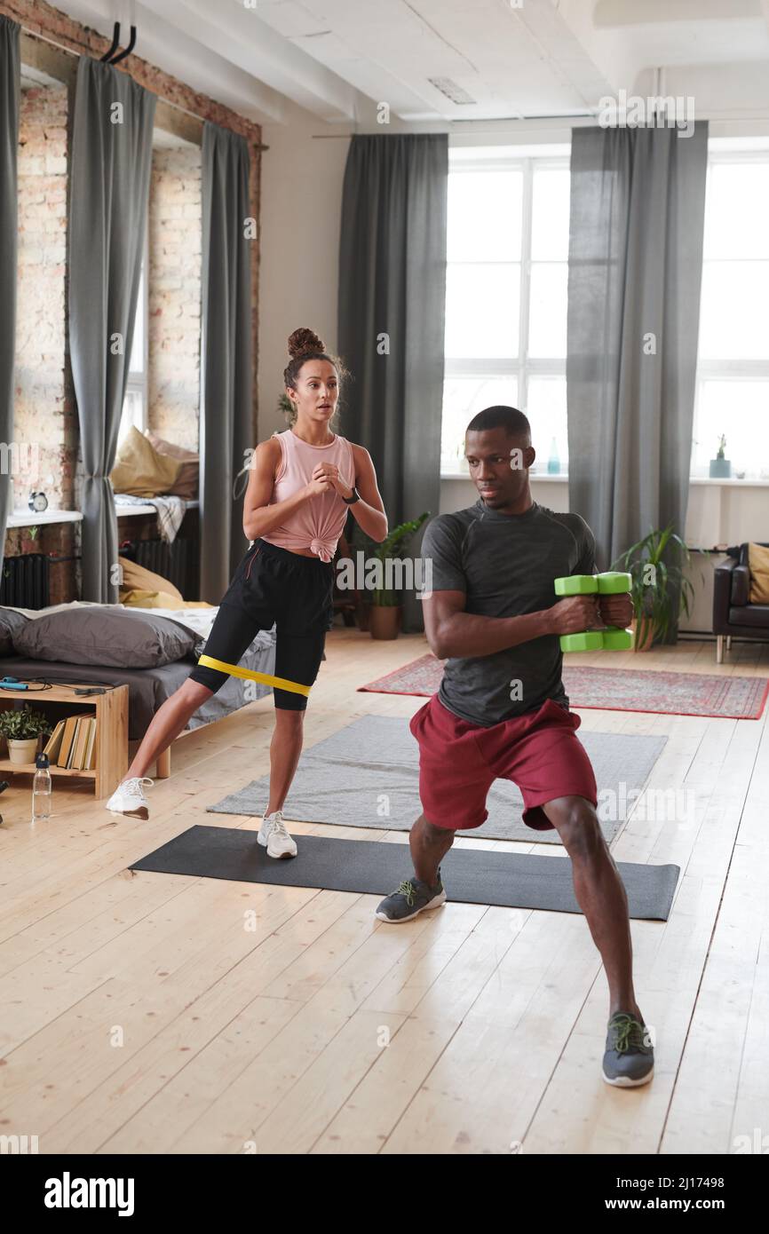 Vertical shot of sporty couple doing strengthening exercises in loft ...