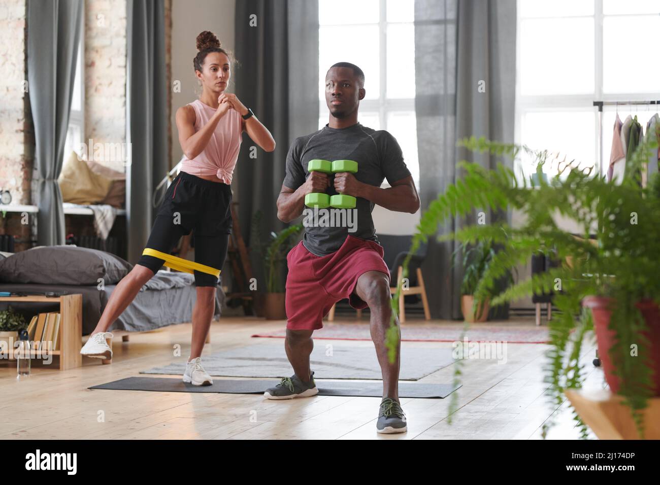 Sporty man and woman doing strengthening exercises in loft living room ...