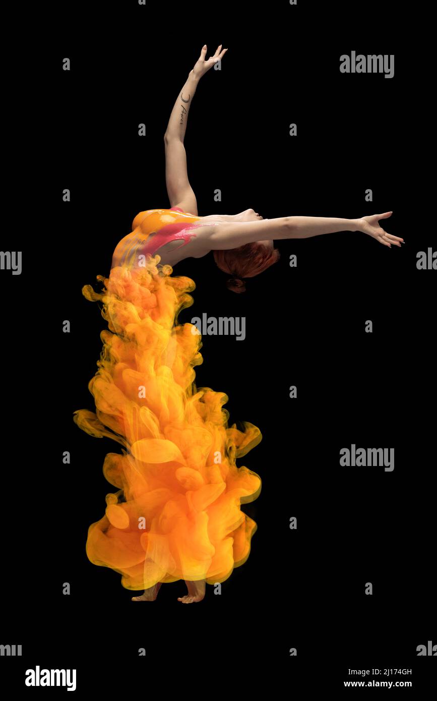 Full-length portrait of young emotive woman covered with orange dye ...