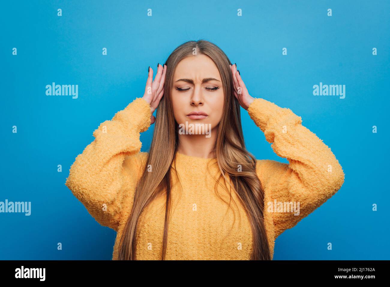 Woman frowning from suffering terrible headache while standing over an ...