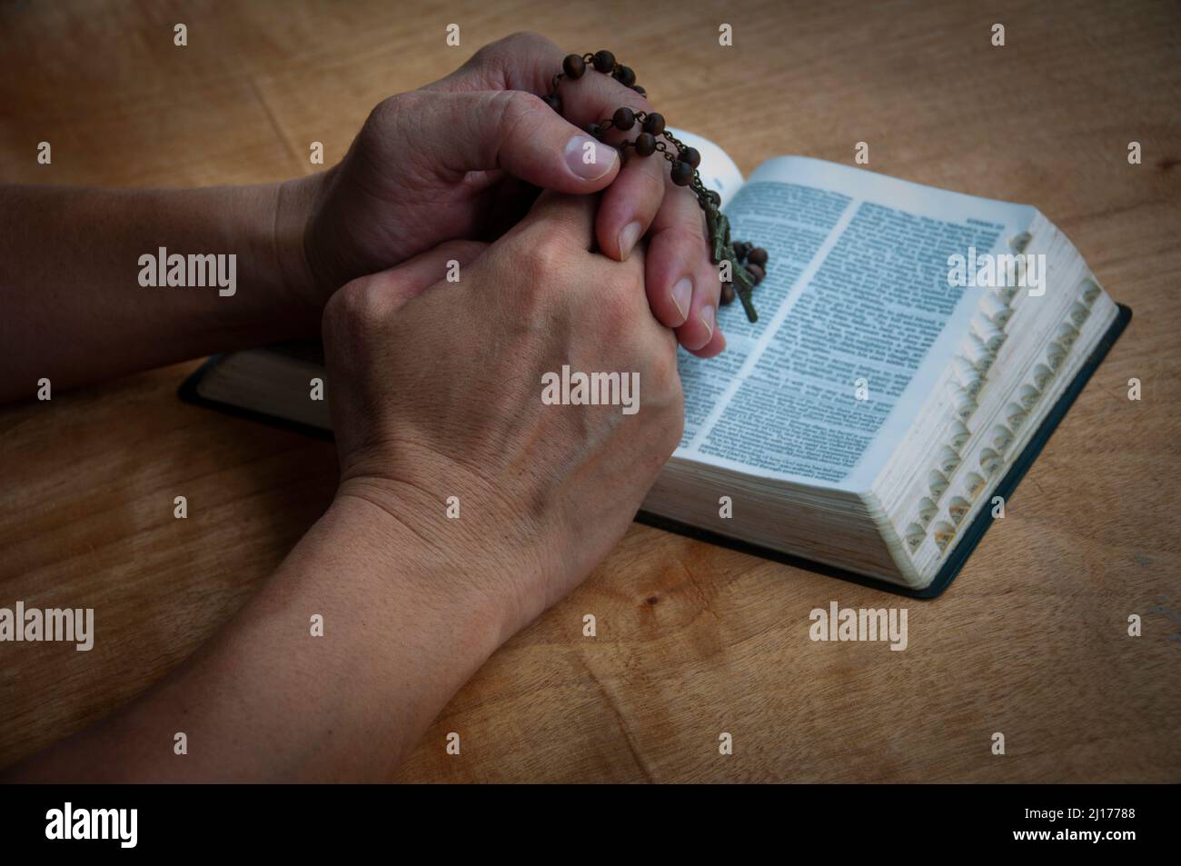 Hand holding Rosary on a Holy Bible praying. Christianity and prayer ...