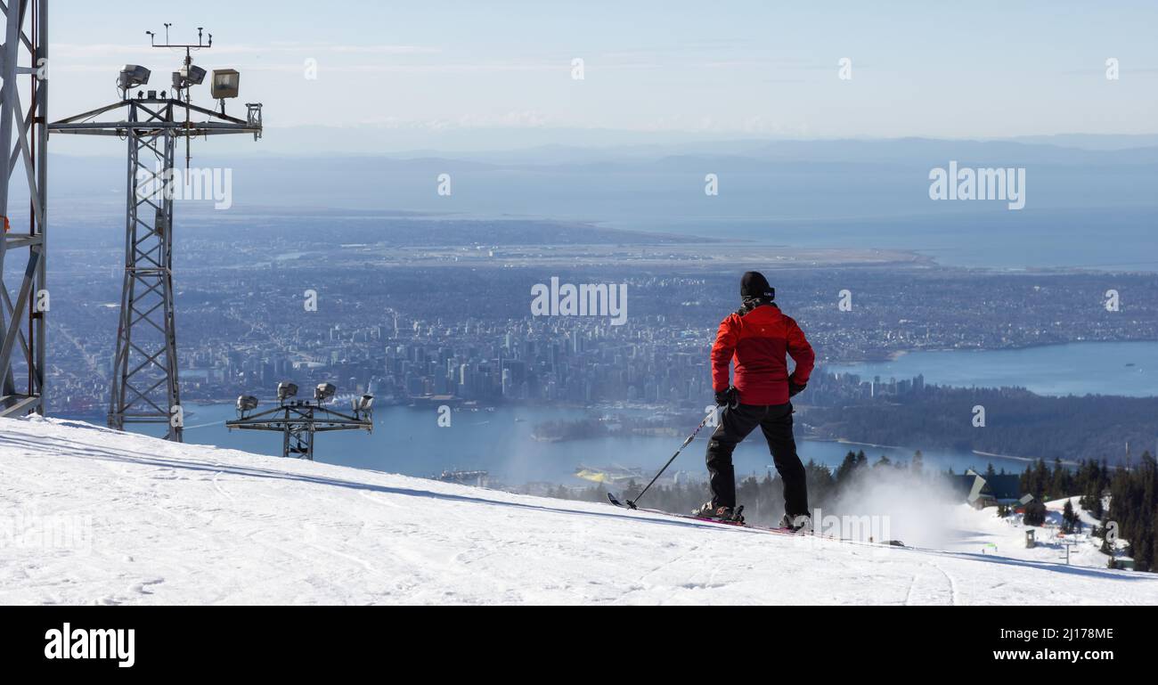 Skiier riding the snowy mountain with the city in background. Sunny ...