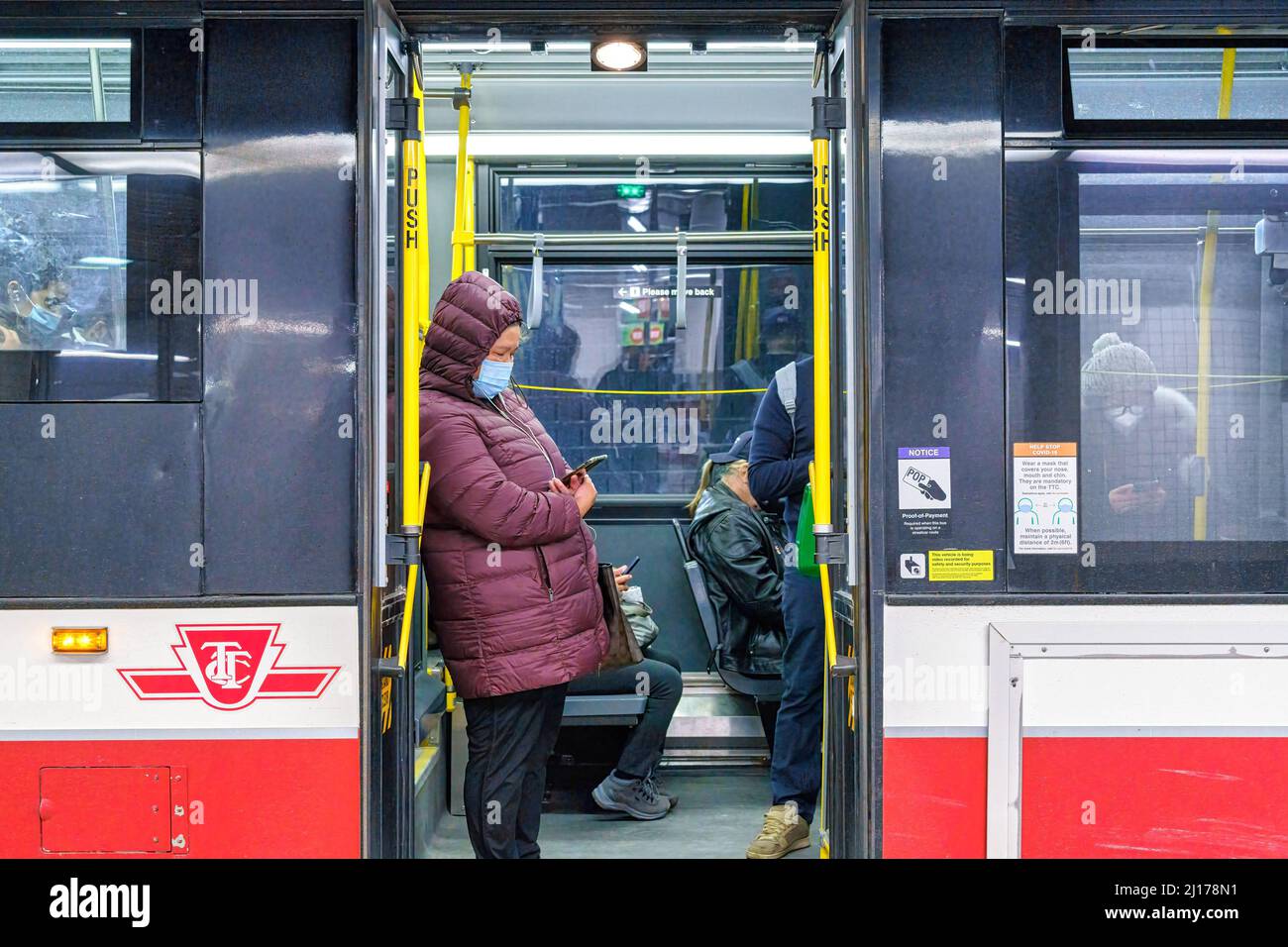 A woman with a face mask standing in the open door of a TTC (Toronto ...