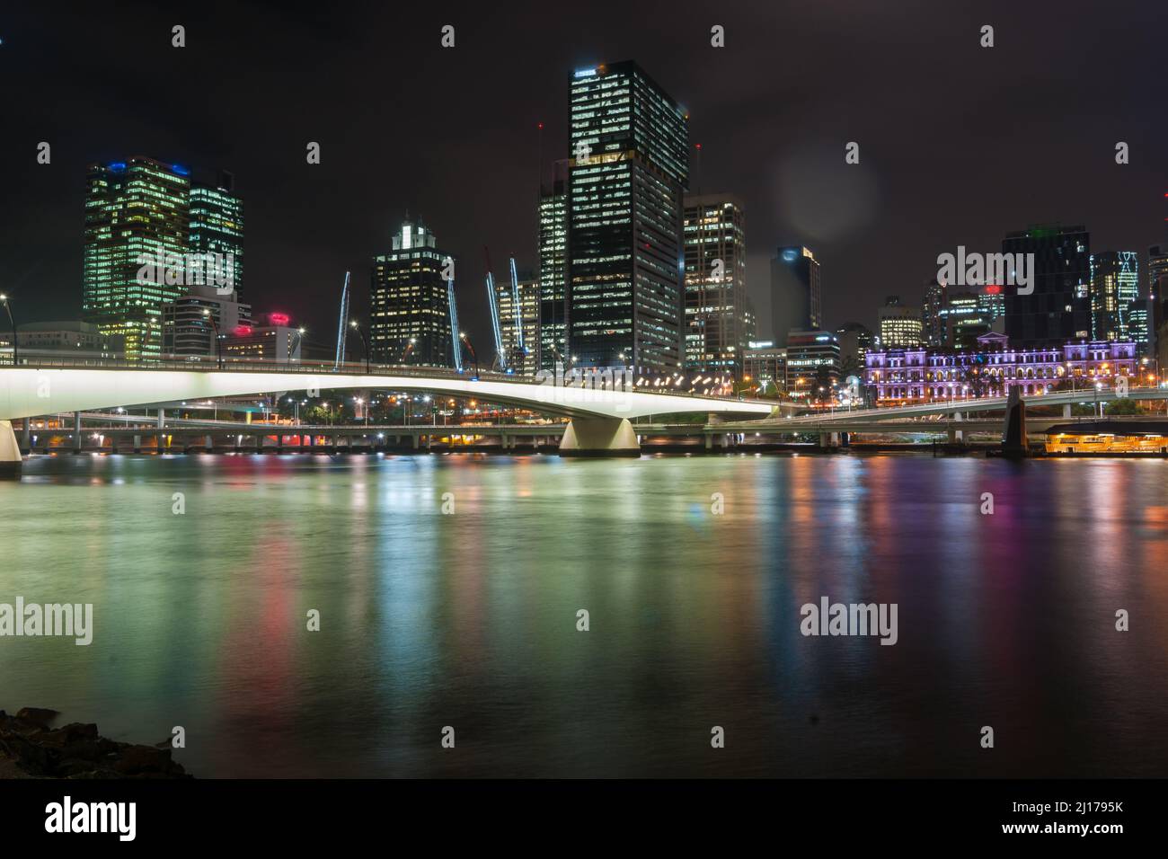 Brisbane Victoria Bridge illuminated against dark and city building ...