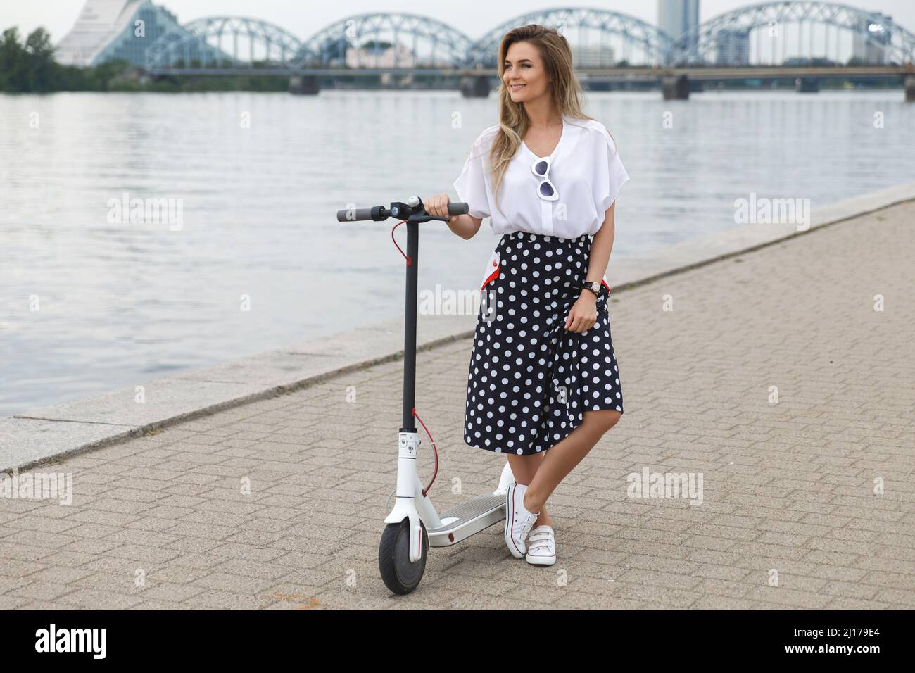 Stylish woman with electric scooter on the riverside Stock Photo - Alamy