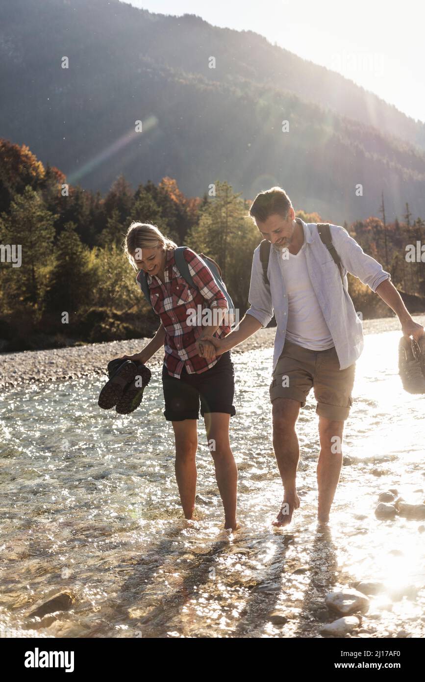 Austria, Alps, couple on a hiking trip wading in a brook Stock Photo ...
