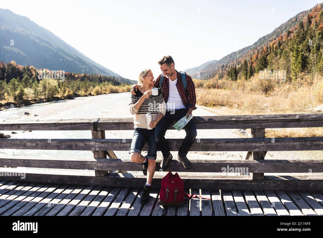 Austria, Alps, couple on a hiking trip having a break on a bridge Stock ...