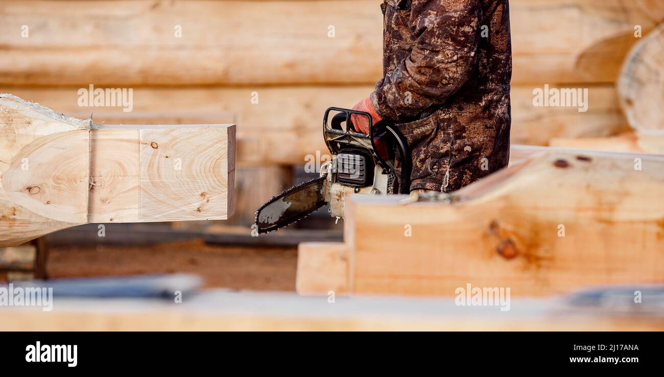 Industrial work carpenter sawing with chainsaw log, construction frame ...
