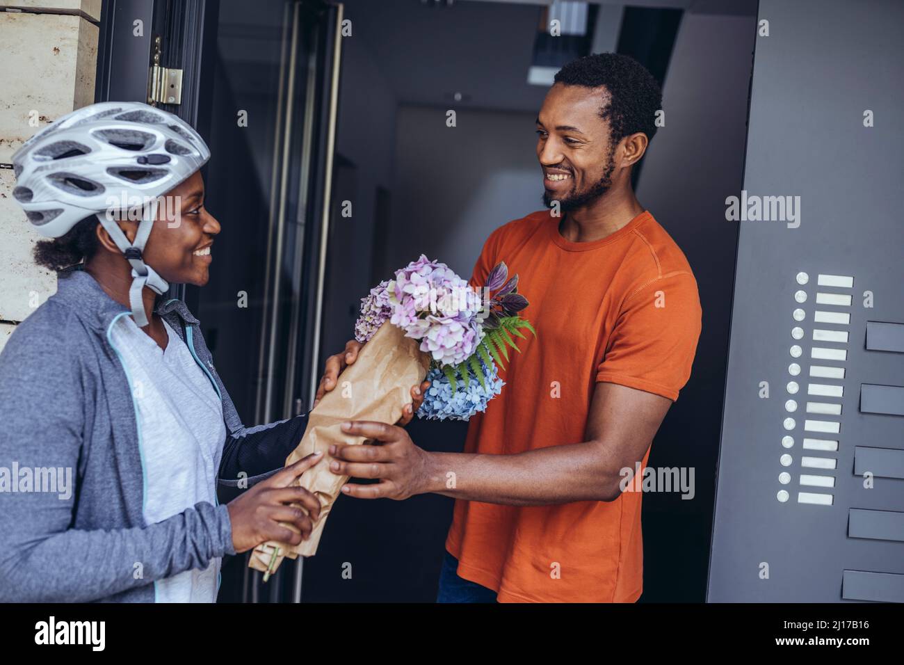 Delivery woman giving flower bouquet at doorway Stock Photo - Alamy