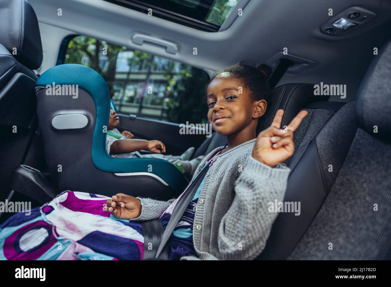 Smiling girl doing peace sign sitting in car Stock Photo - Alamy