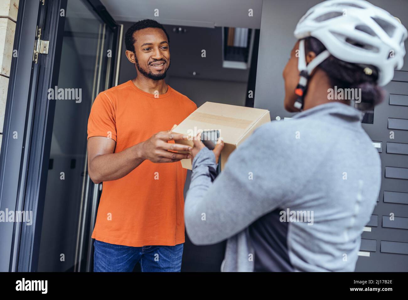 Customer receiving package box from delivery woman at doorway Stock ...