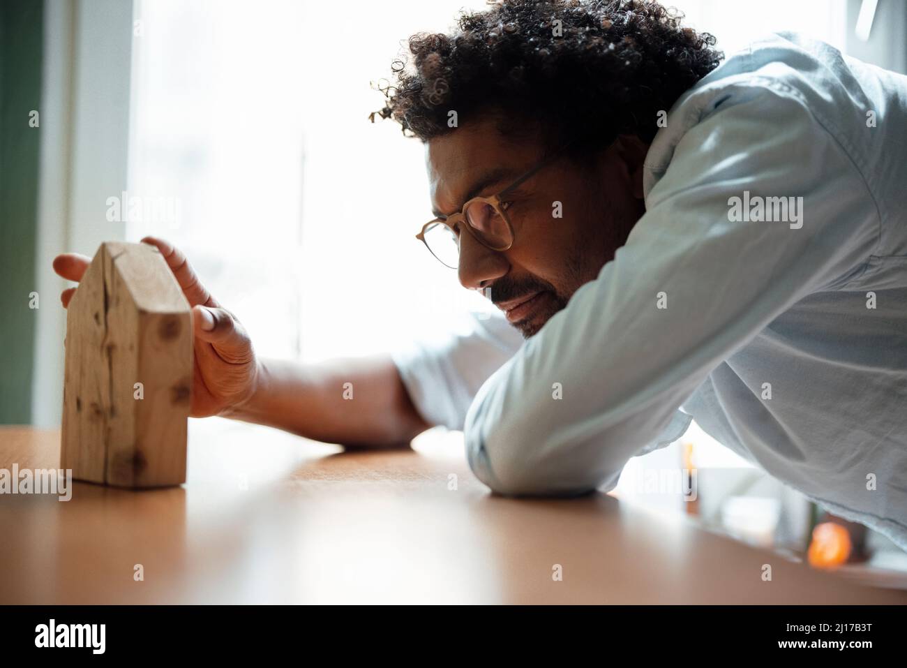 Man leaning on table looking at model house at home Stock Photo - Alamy