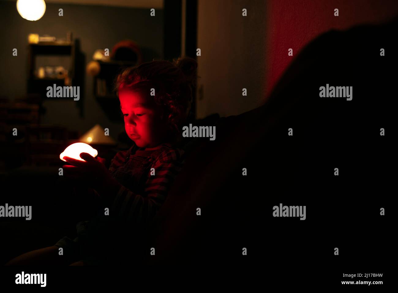 Boy holding illuminated toy in dark room at home Stock Photo - Alamy