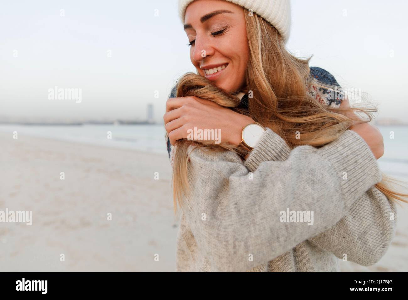 Happy woman with eyes closed hugging self at beach Stock Photo - Alamy