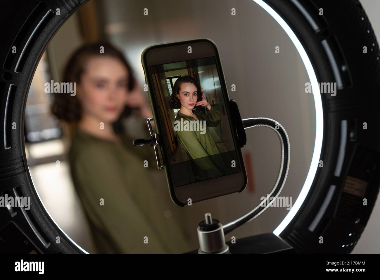 Young influencer photographing herself through mobile phone at home ...